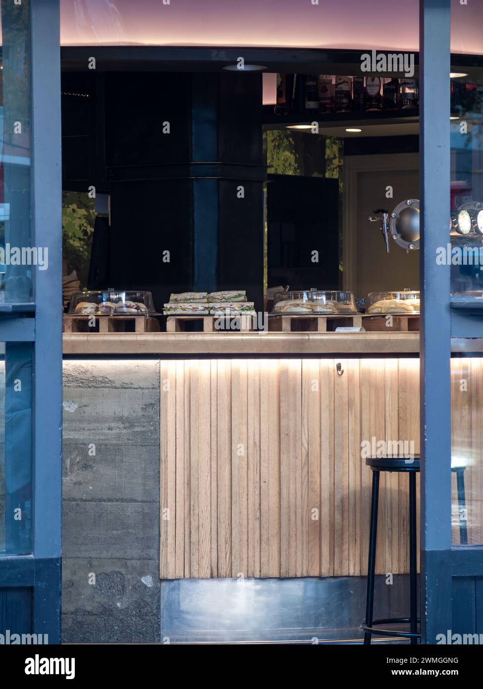 cozy, well-lit café bar with various pastries displayed, wooden design ...