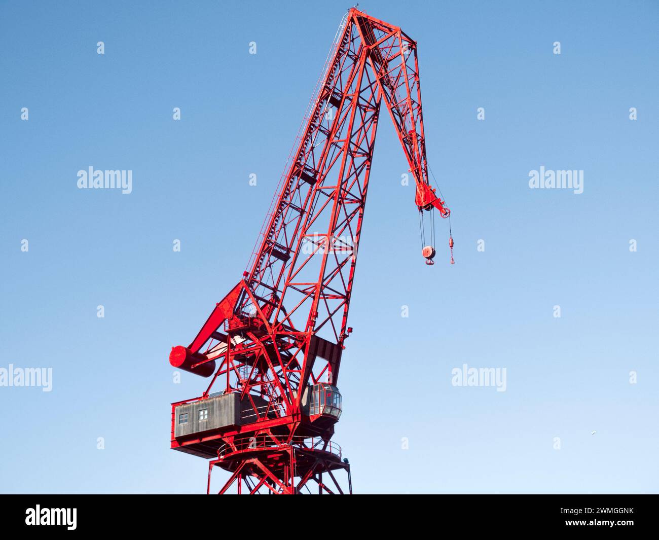 red crane against a clear blue sky, its structure and machinery ...