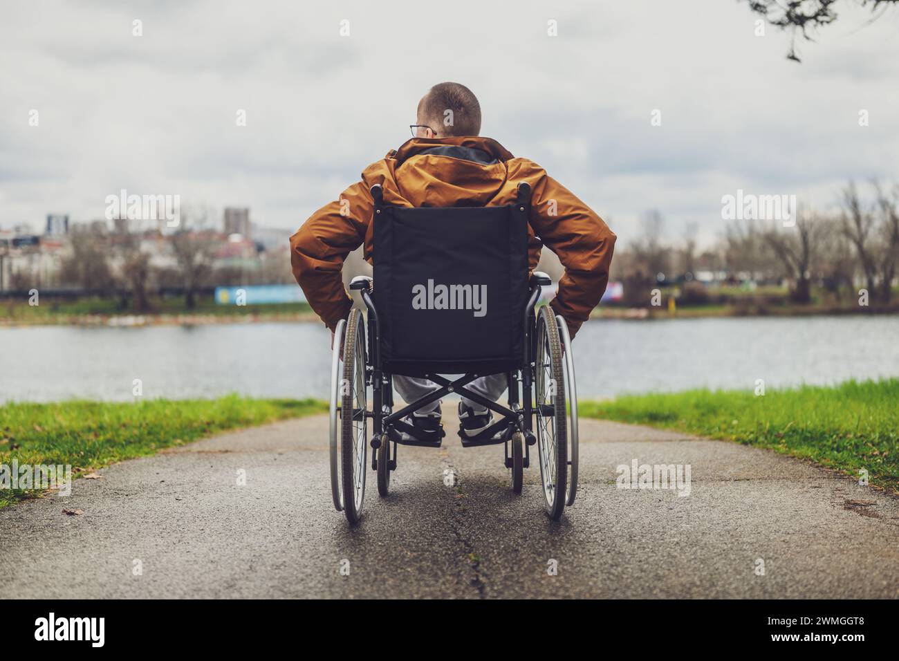 Rear view image of paraplegic handicapped man in wheelchair by the lake ...