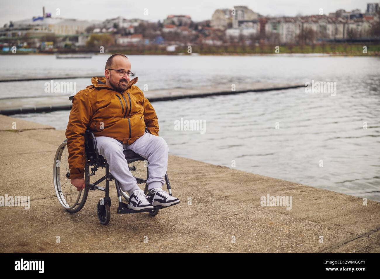 Happy paraplegic handicapped man in wheelchair by the lake. He is ...