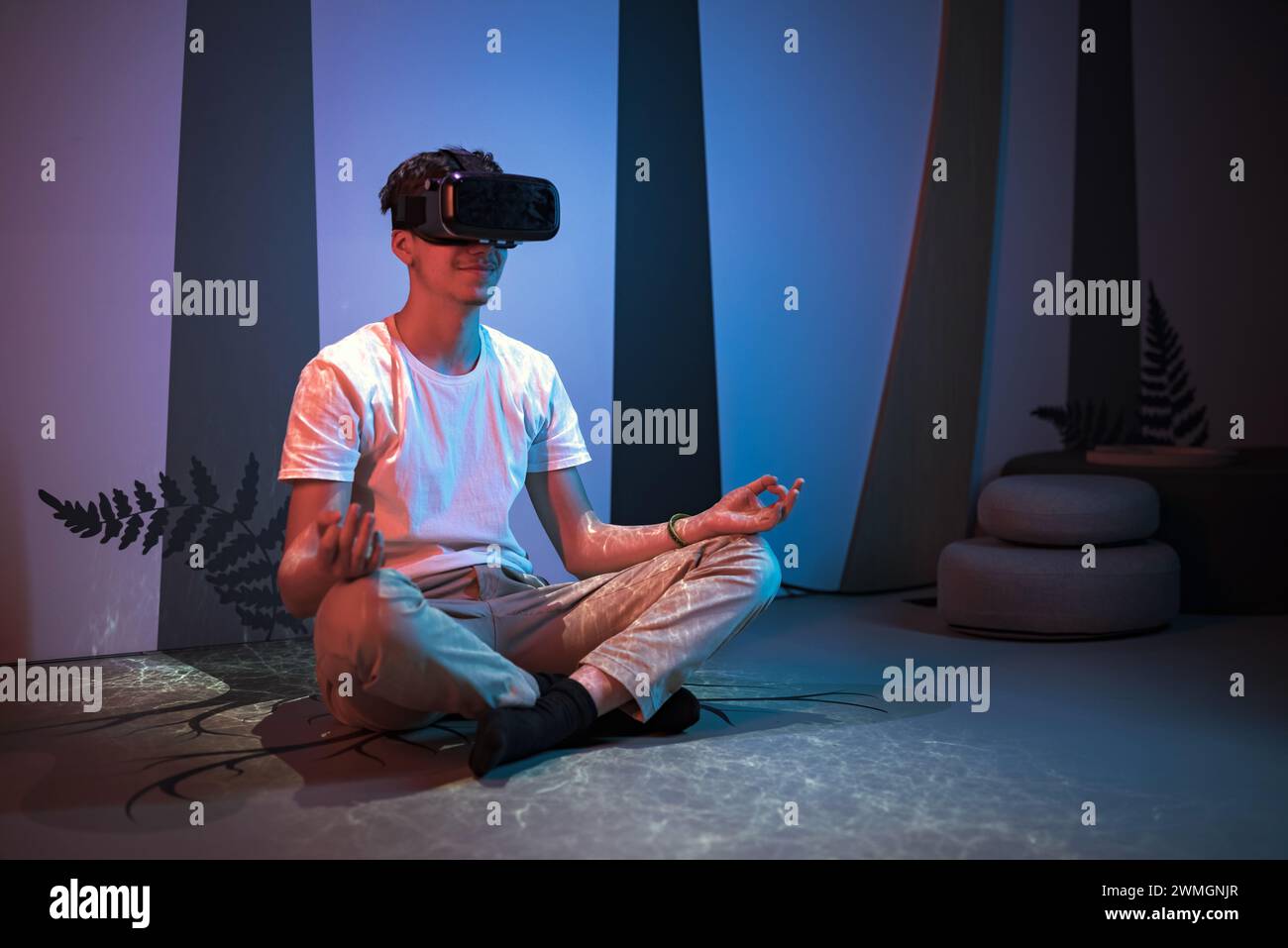 Smiling teenage programmer boy sitting on the floor with a virtual ...