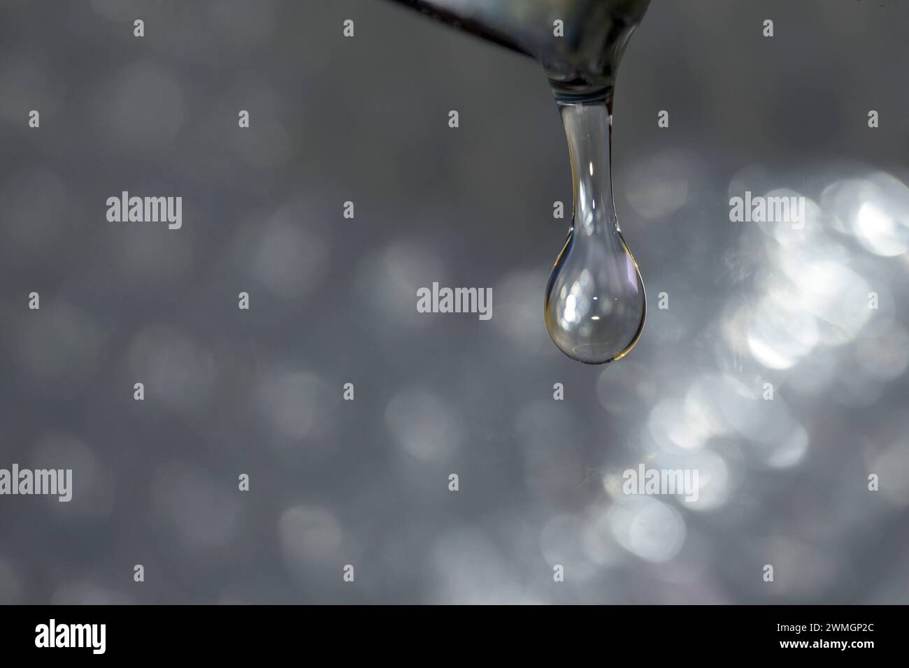 Detail of small water drop coming out of dripping faucet with bright ...