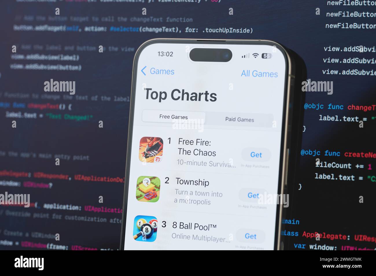New York, USA - February 23, 2024: Top chart games on iphone screen in blurred code programming ...