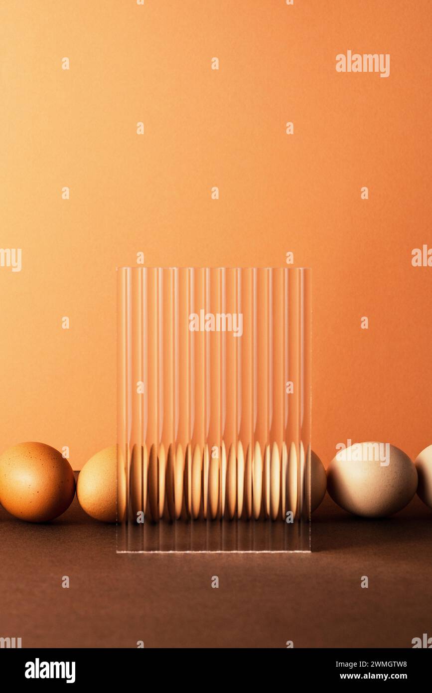 Eggs in a row behind a corrugated glass, refraction and shadow on brown ...