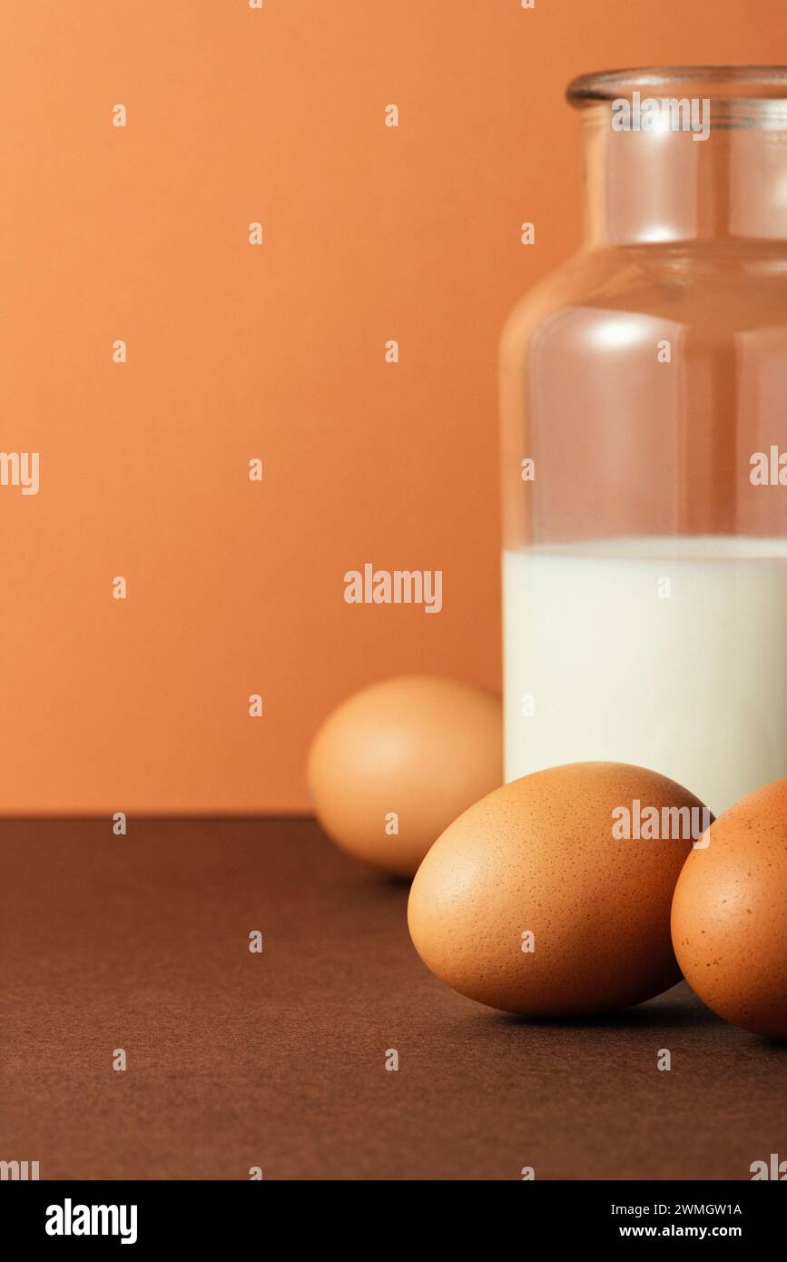 Three eggs with milk in glass bottle on brown background, studio shot ...
