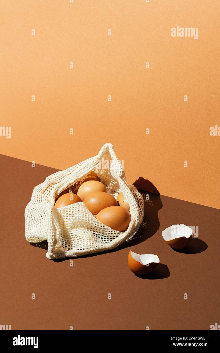 Eggs in a mesh bag with broken egg shells on brown background. Sun ...