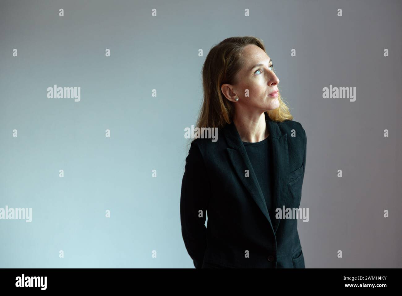 Portrait in profile of an adult attractive young woman in a black suit ...