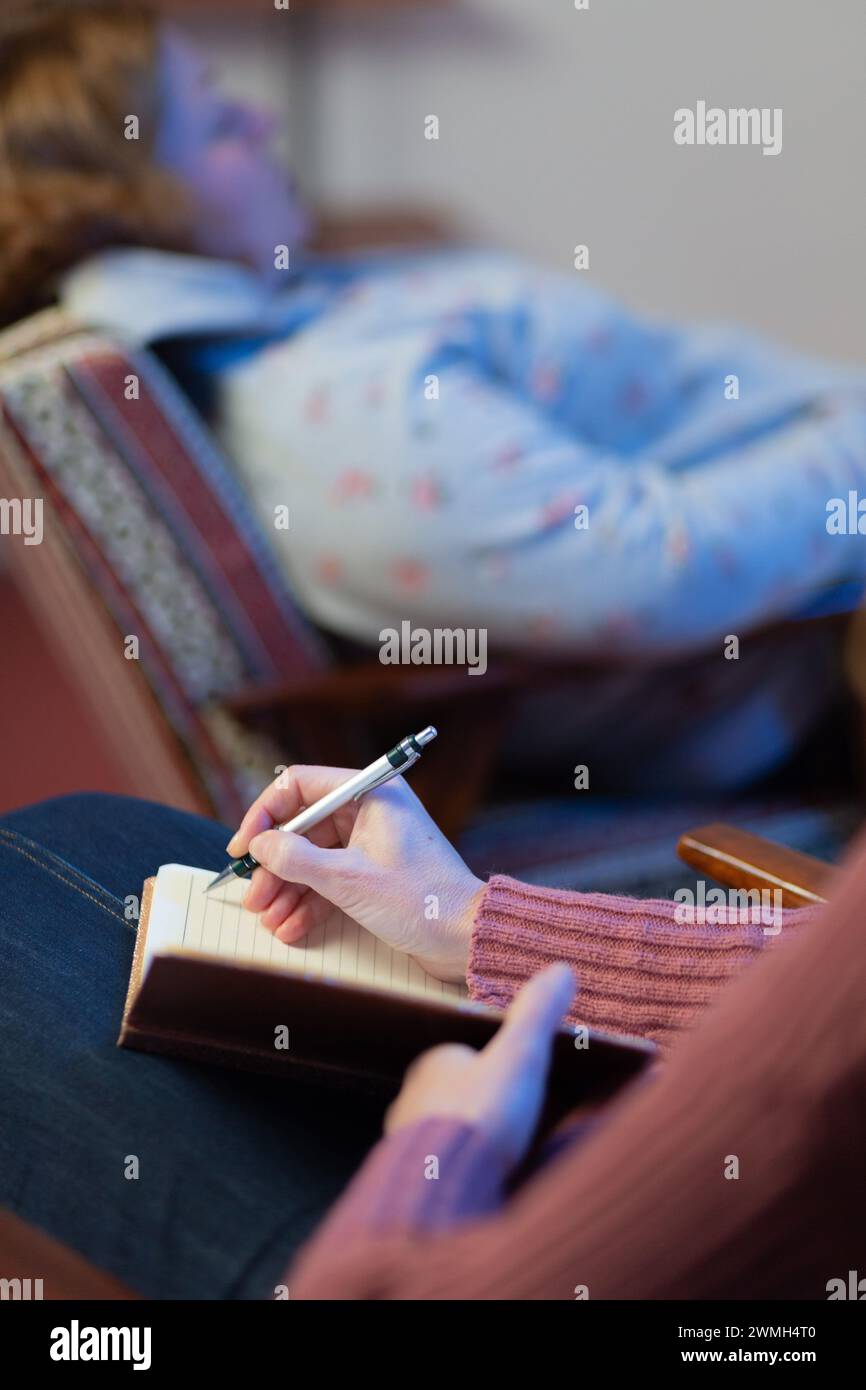 An adult female psychologist interviews a female patient and takes ...