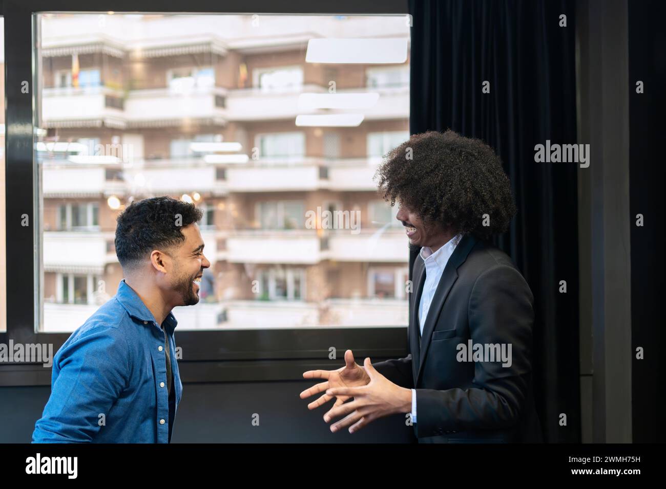 Two diverse professionals laughing and talking, with one in a blue ...