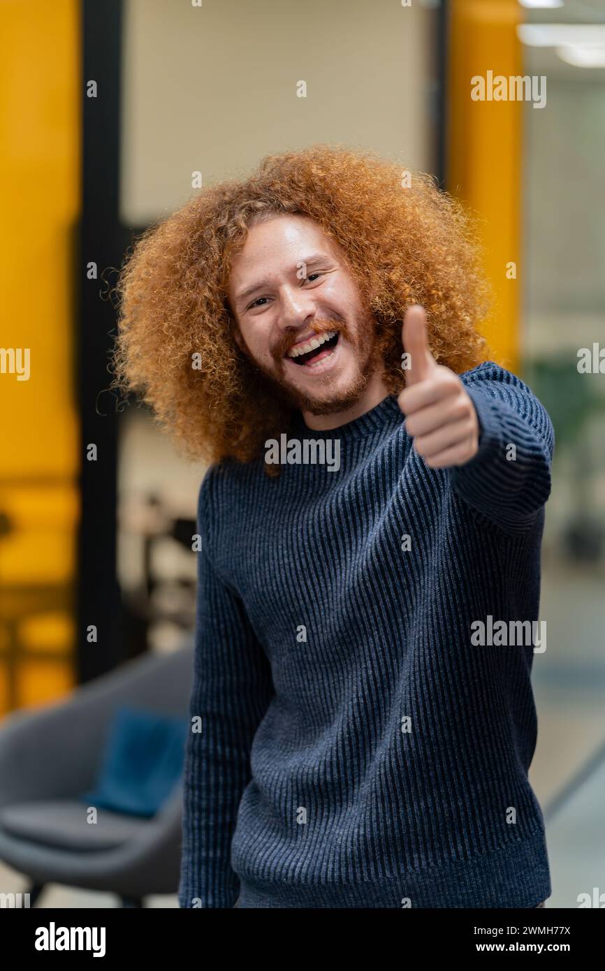 Exuberant man with thick curly hair laughing and giving a thumbs-up in ...