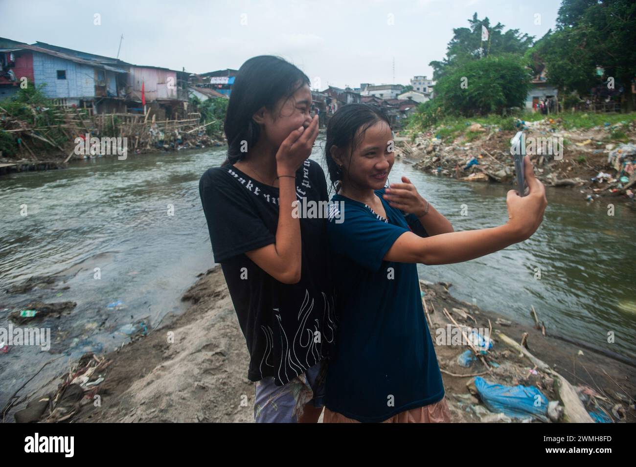 Two teenage girls pose with their cellphones in the Deli River which is ...