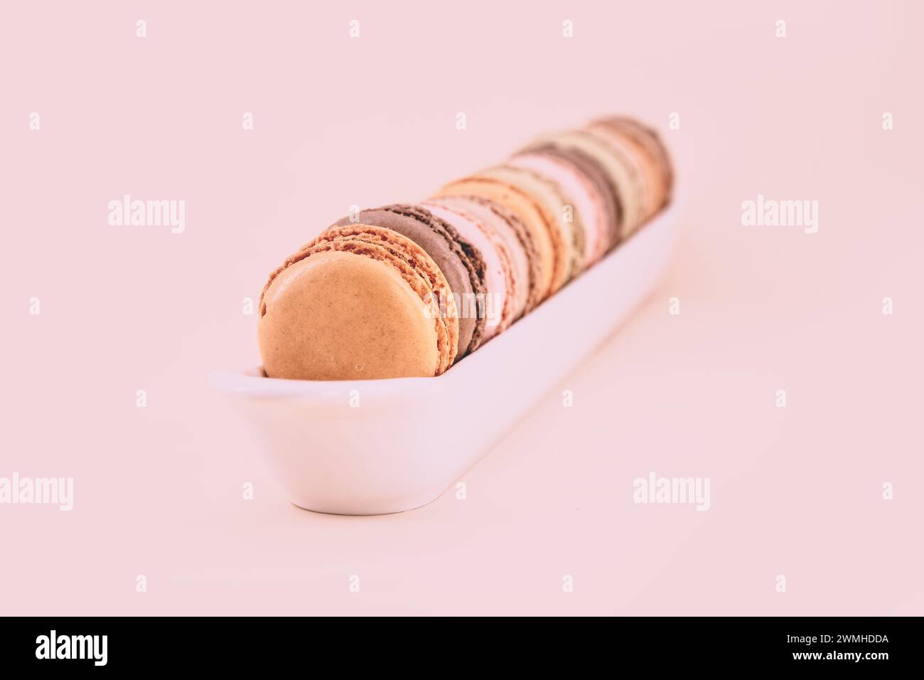 Brown and orange french macaroons on a plain pastel colored background ...