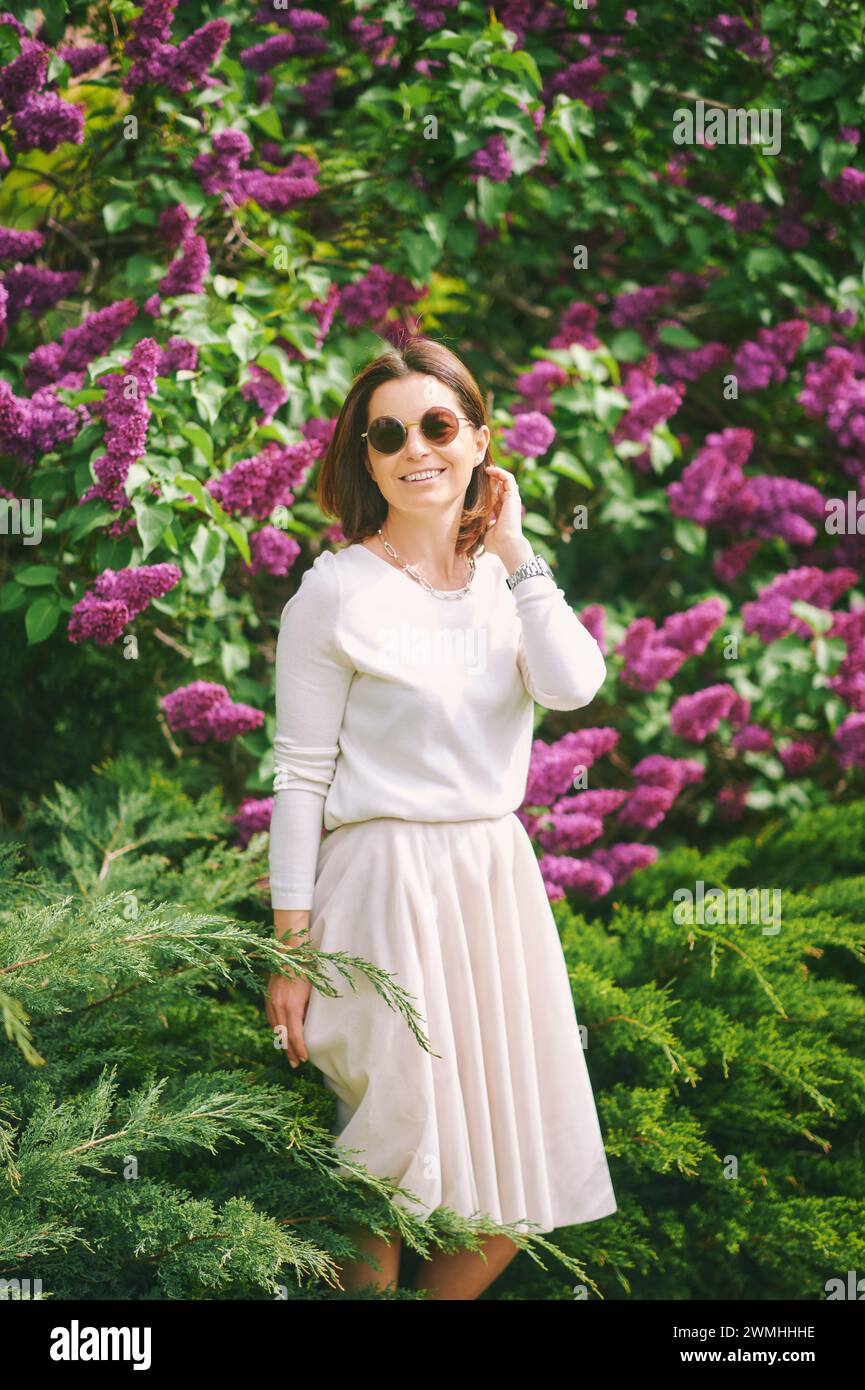 Spring portrait of pretty mature woman posing with lilac flowers on ...