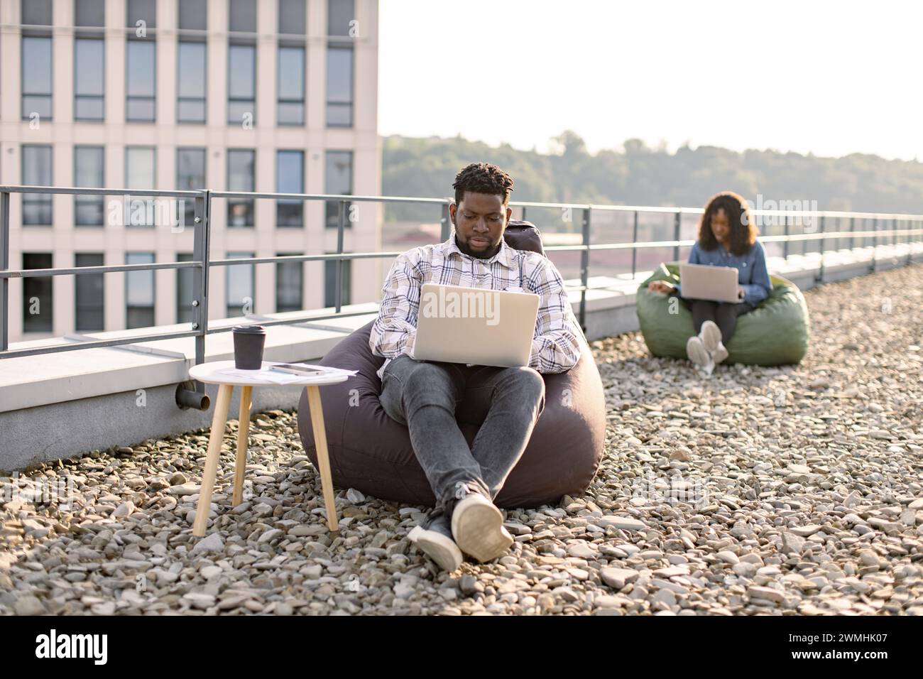 Business man sitting at chair bag on roof top outdoors and typing on ...