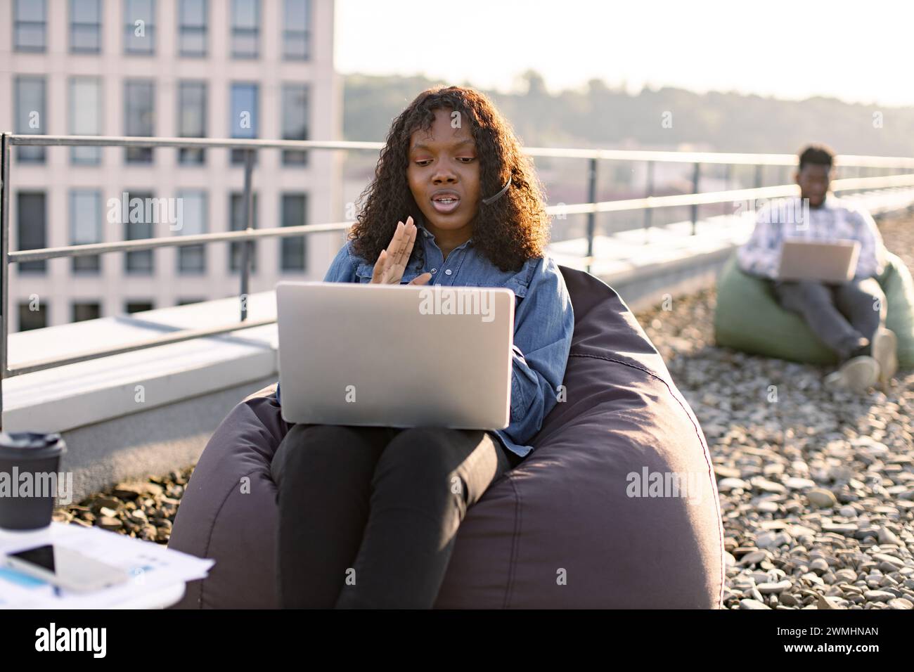 Focused African female wearing denim shirt and headset holding online ...