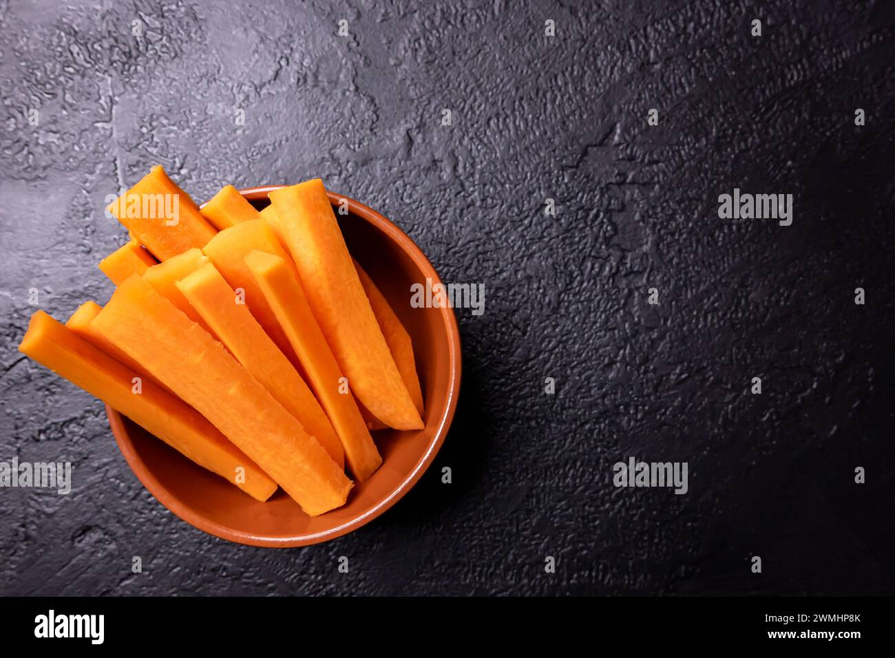 Carrot pieces on a dark background inside a bowl Stock Photo - Alamy
