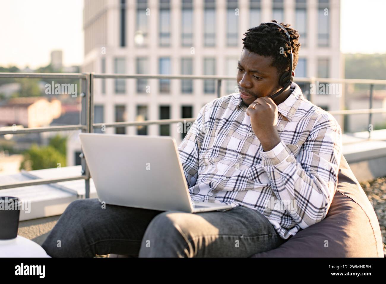 Young African man in casual clothes using portable computer Stock Photo ...