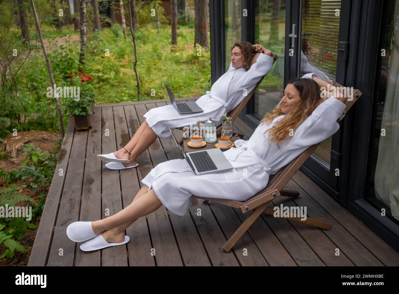 Two women exude relaxation while working on laptops, reclining in ...