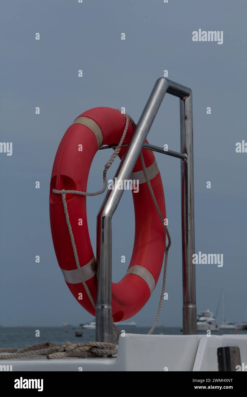 One singular orange safety float tied with ropes to the railing of a ...