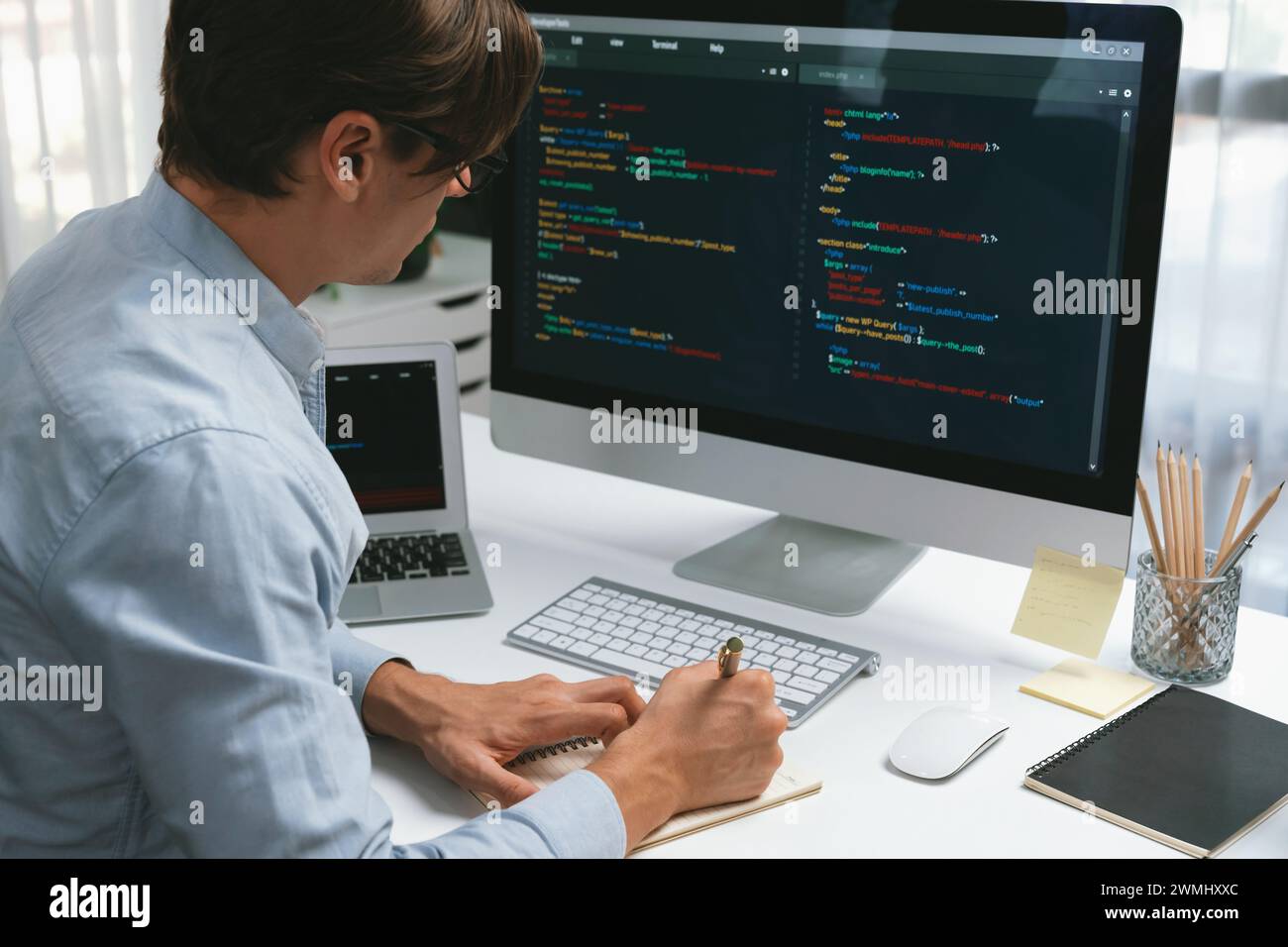 Stressful IT developer analyzing online software development information on pc and laptop with ...