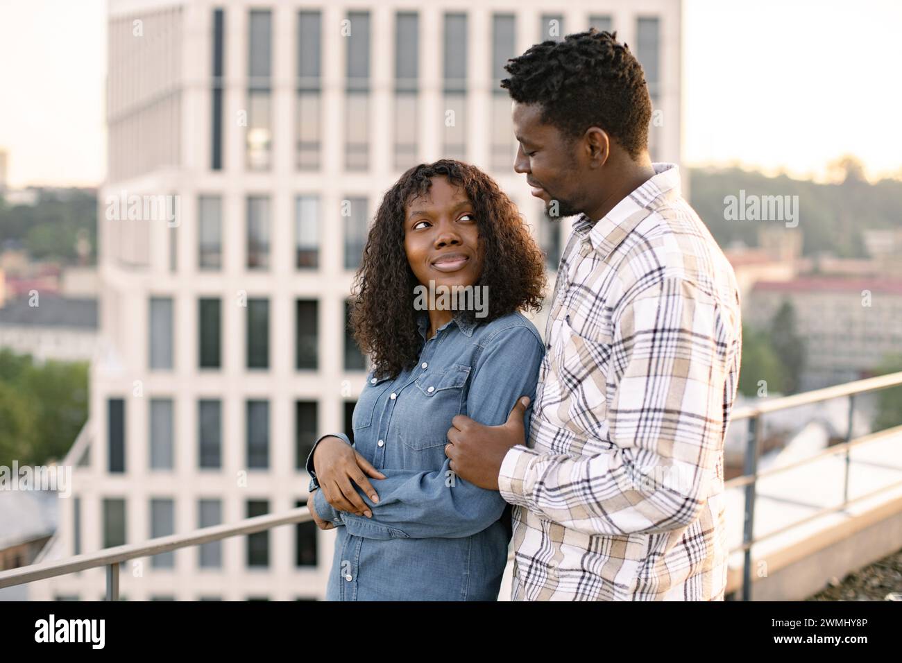 African couple woman and man hugging on rooftop of modern building ...
