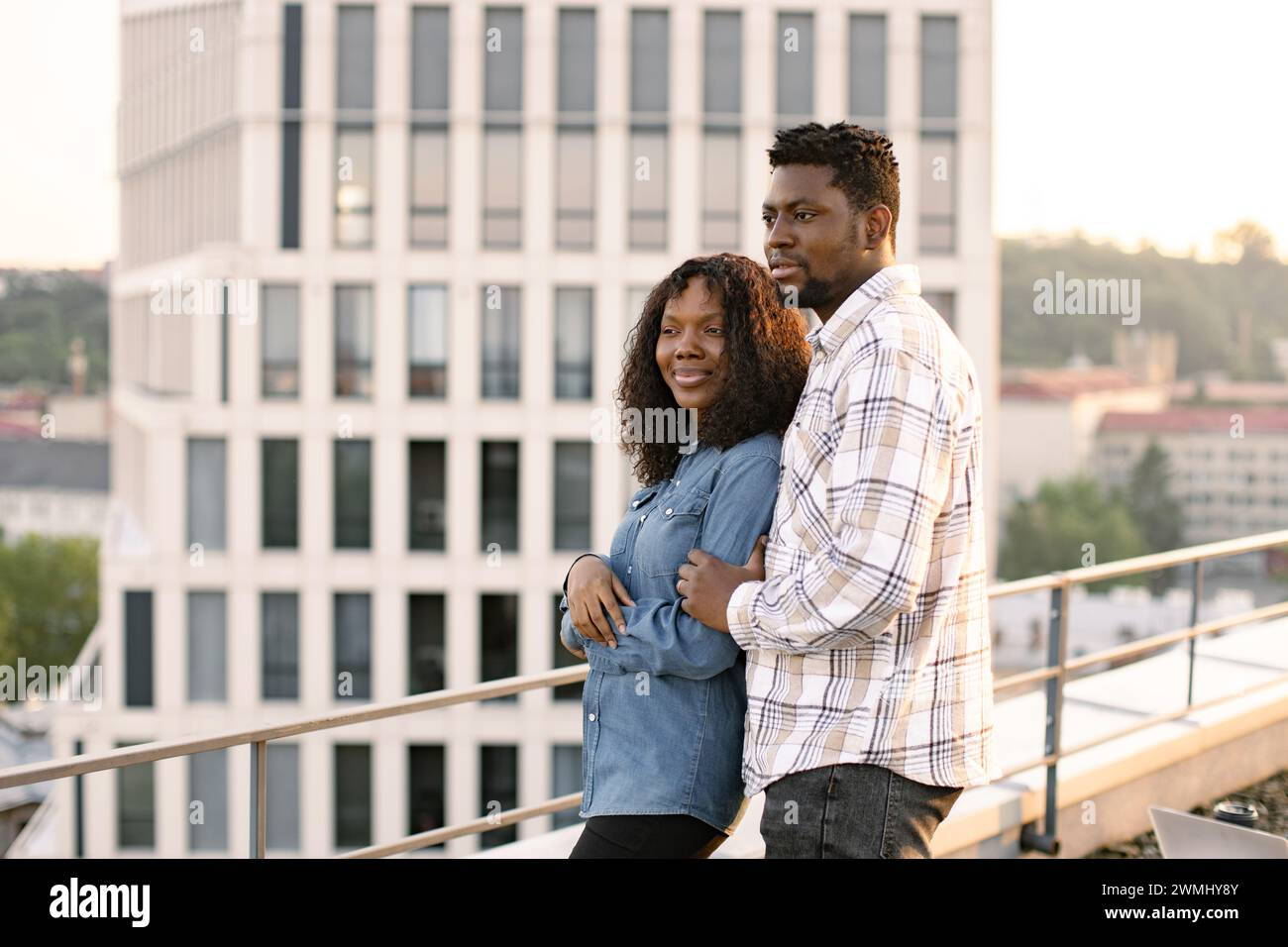 African couple woman and man hugging on rooftop of modern building ...