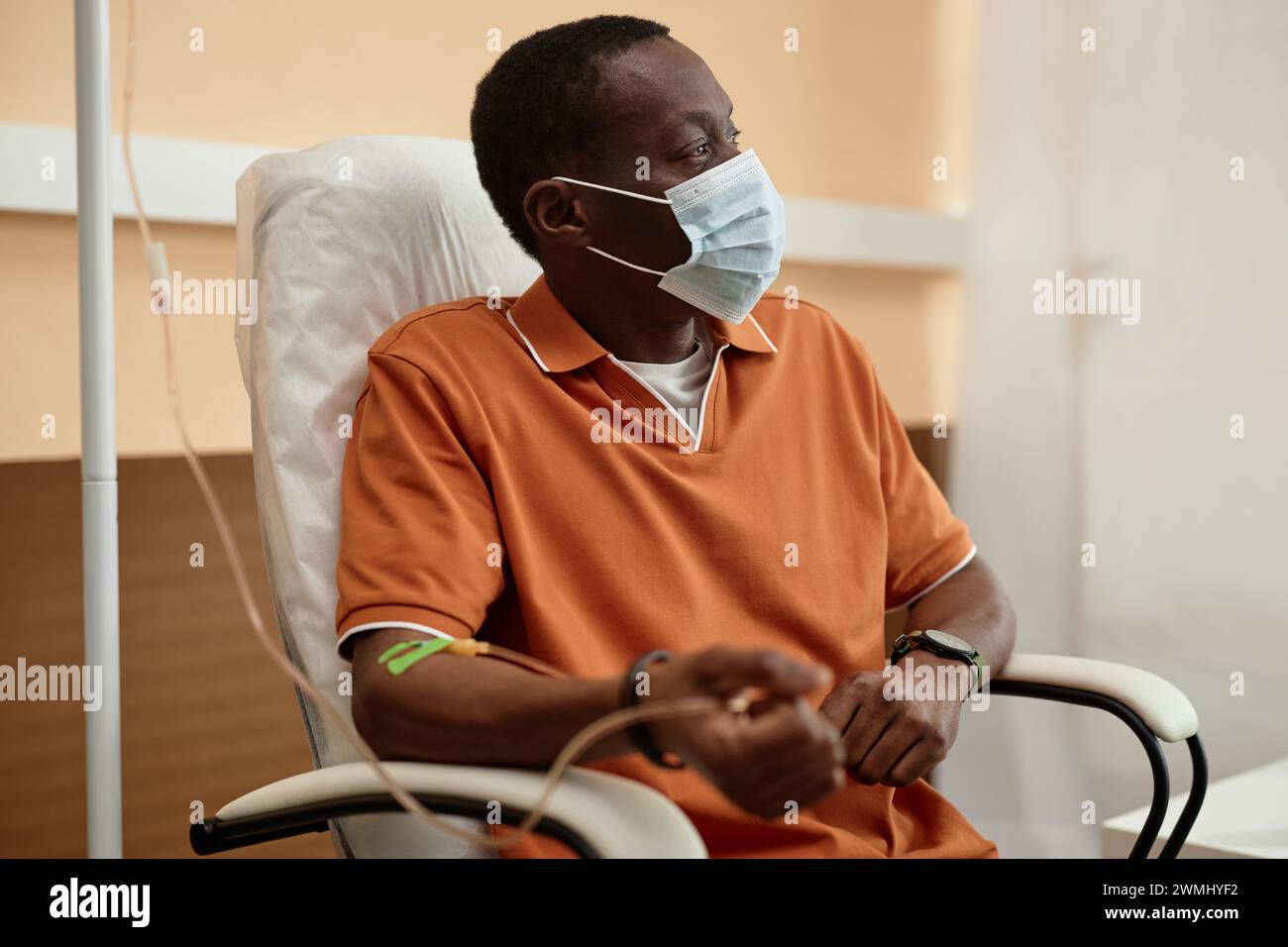 Side view of Adult African American man wearing mask while getting IV ...