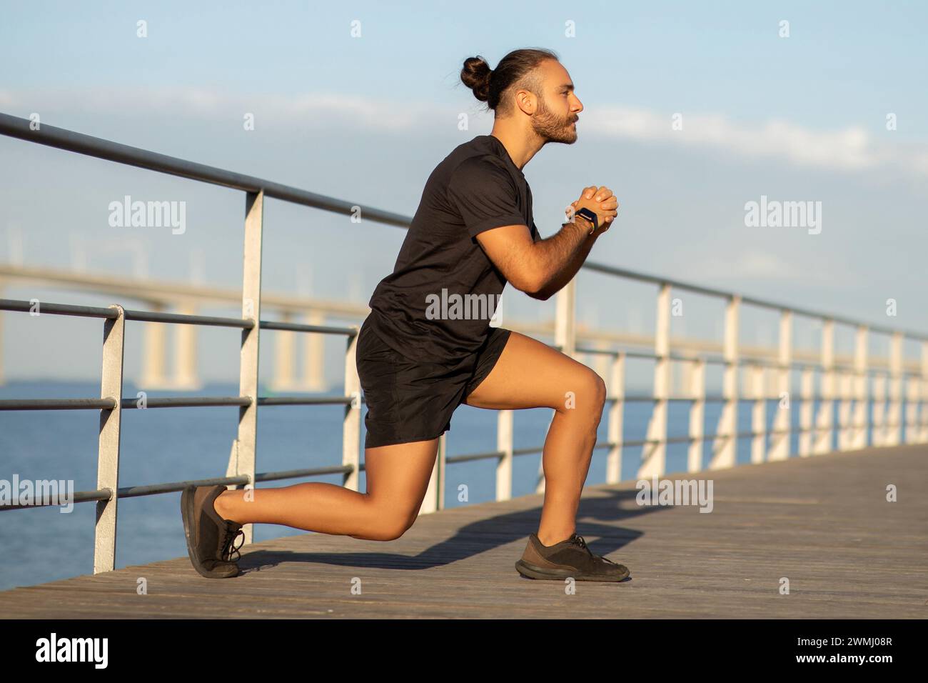 man in sportswear demonstrating a lunge deep exercise by sea Stock ...