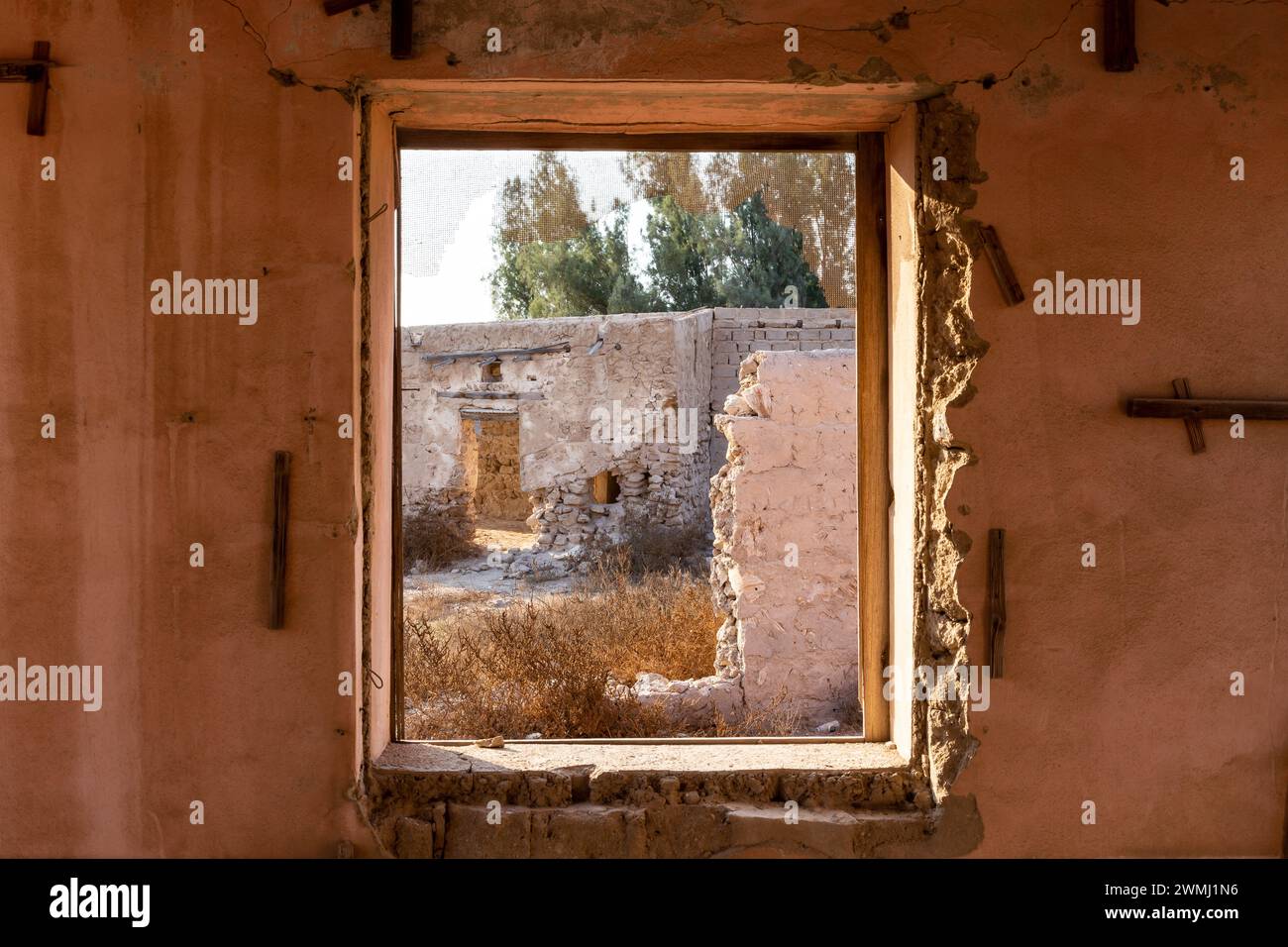 View through a broken window of ruined buildings and courtyard in Al ...