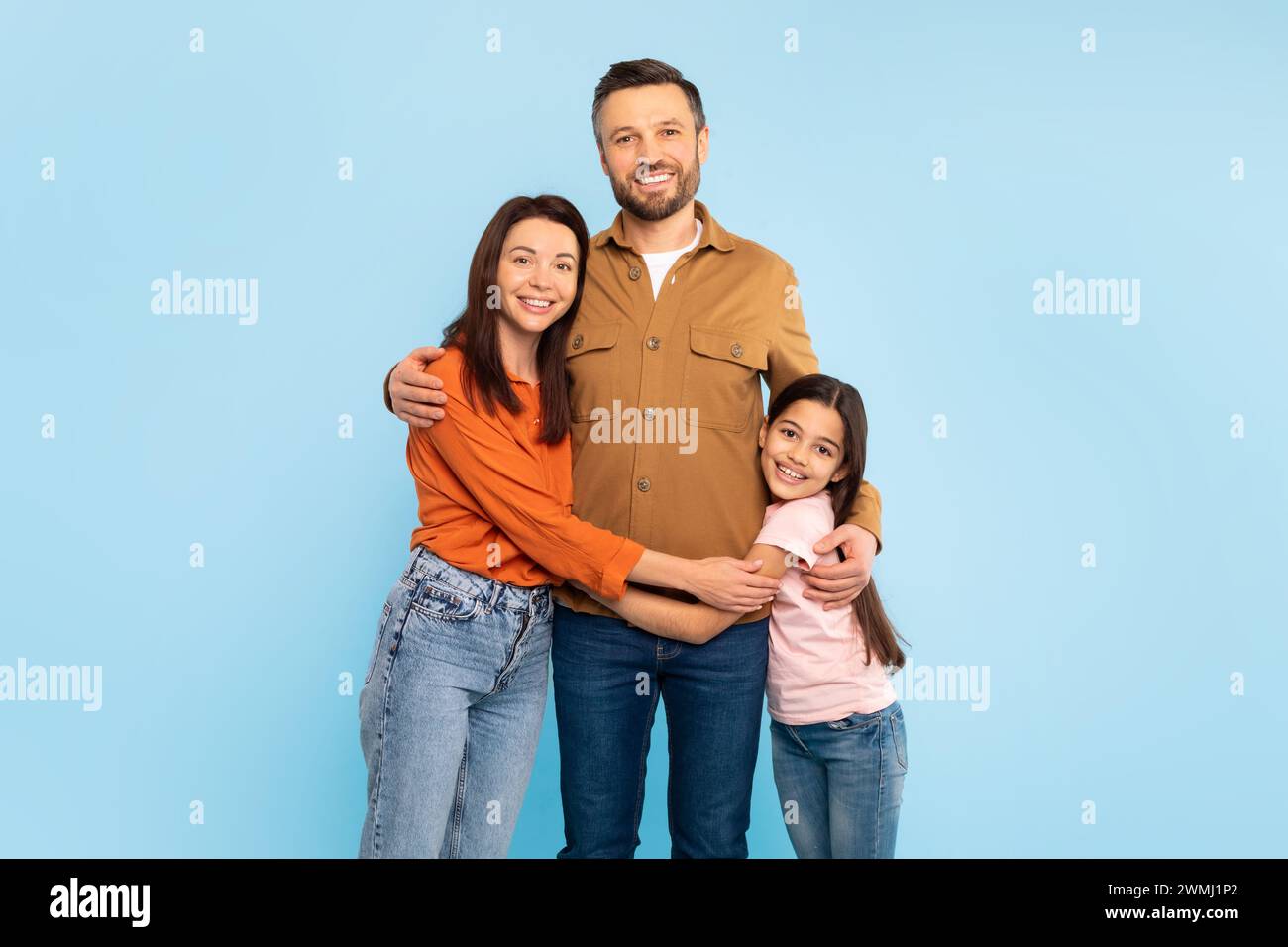 Happy European Family Of Three Standing Embracing Over Blue Backdrop ...