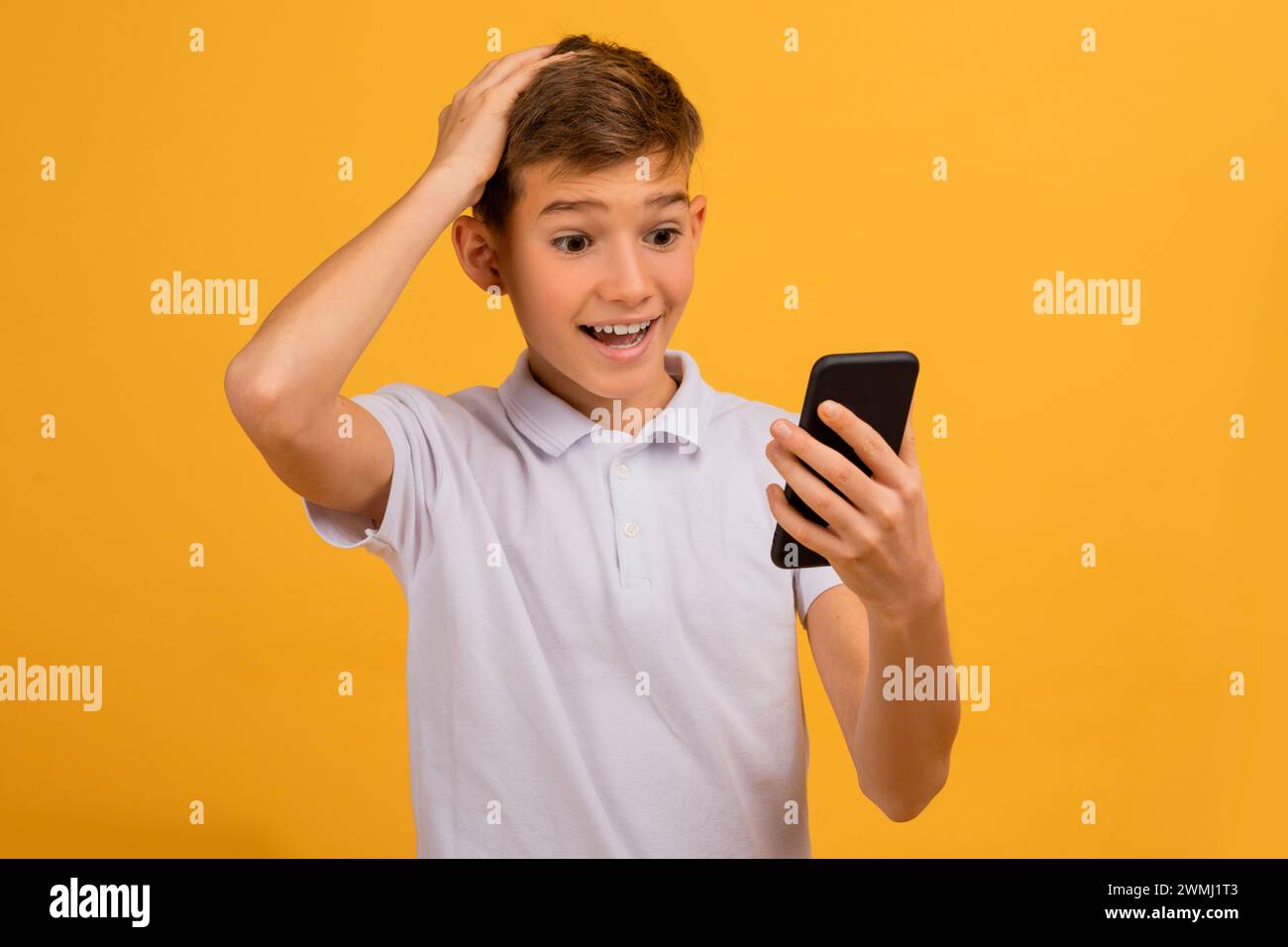 Amazed teen boy looking at smartphone screen and touching head Stock ...