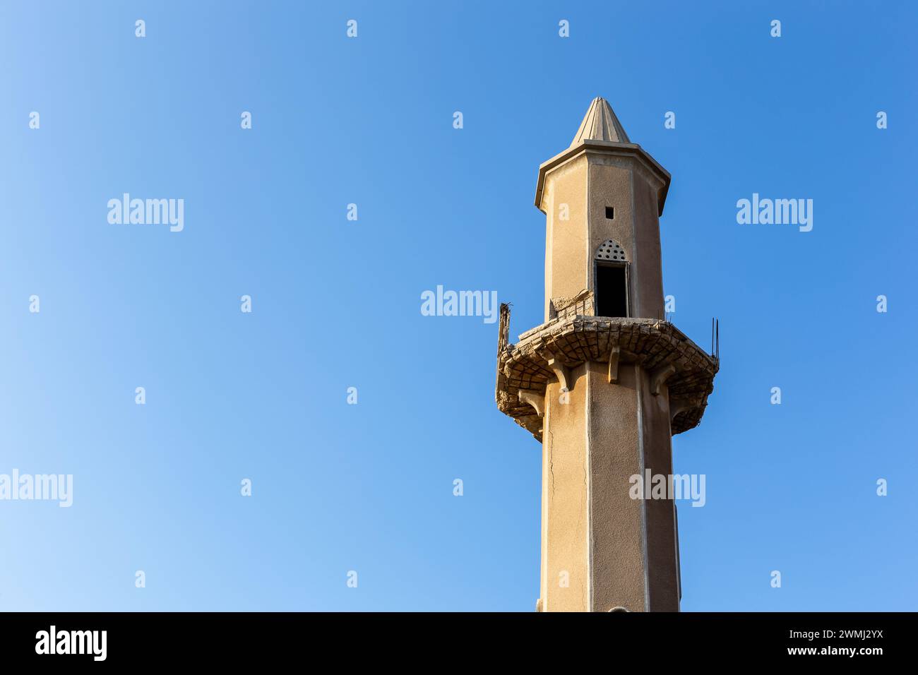 Old destroyed sandstone minaret of a mosque against crystal blue sky ...