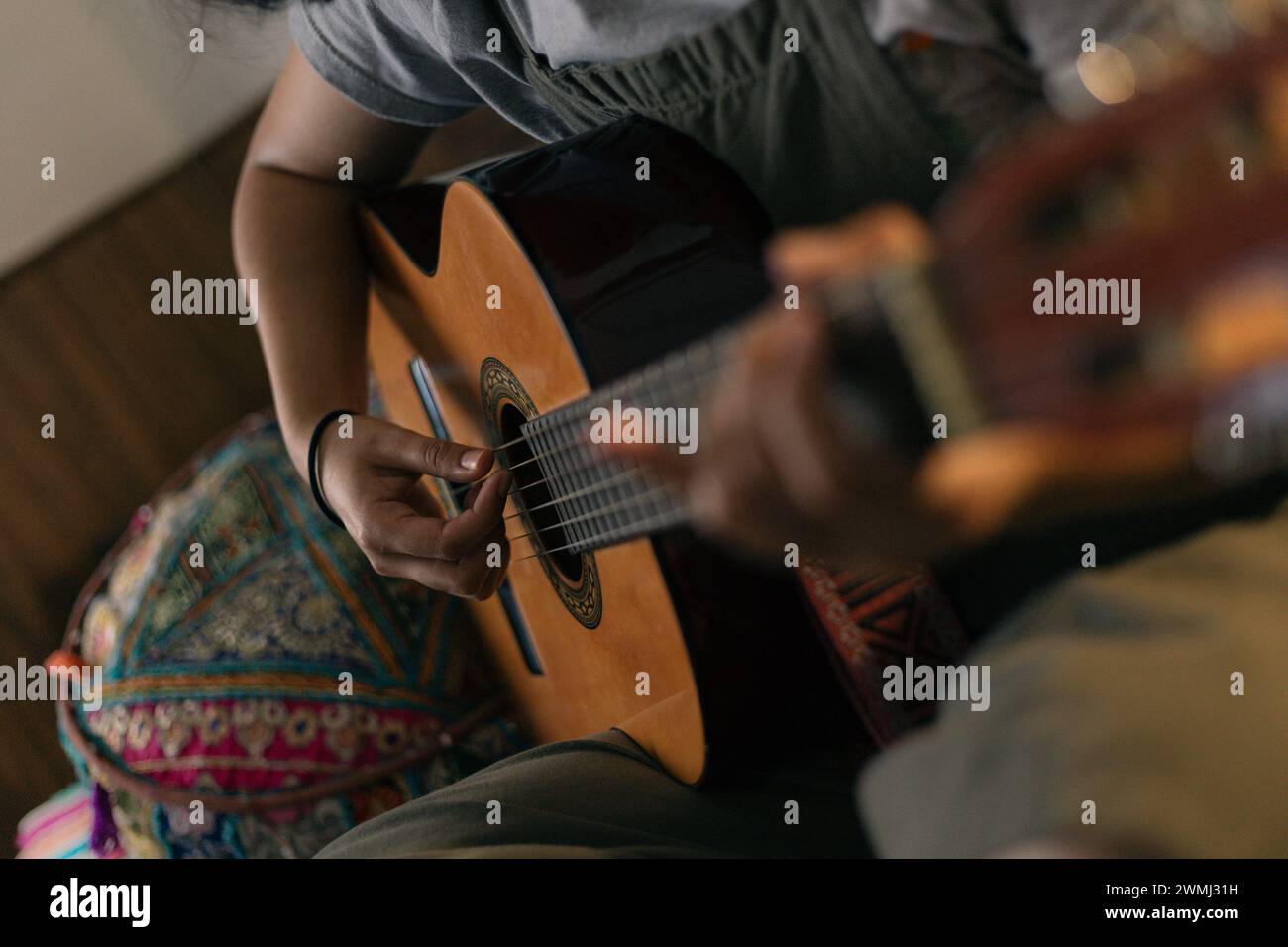 A Girl sitting on the bed playing music on the Creole guitar, pillows ...