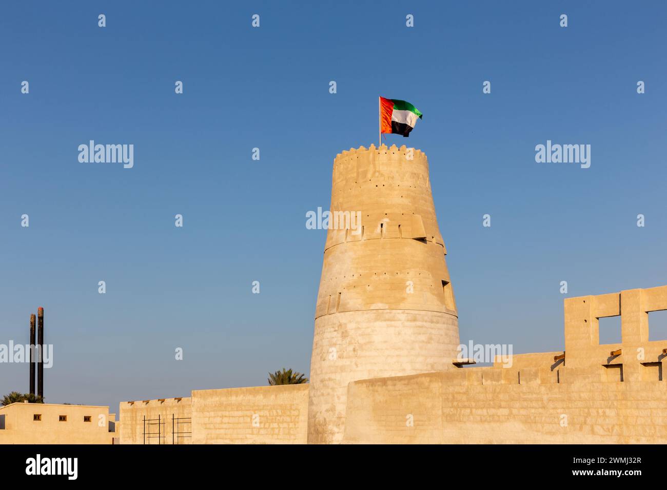 Stone arabic watchtower with waving United Arab Emirates National Flag ...