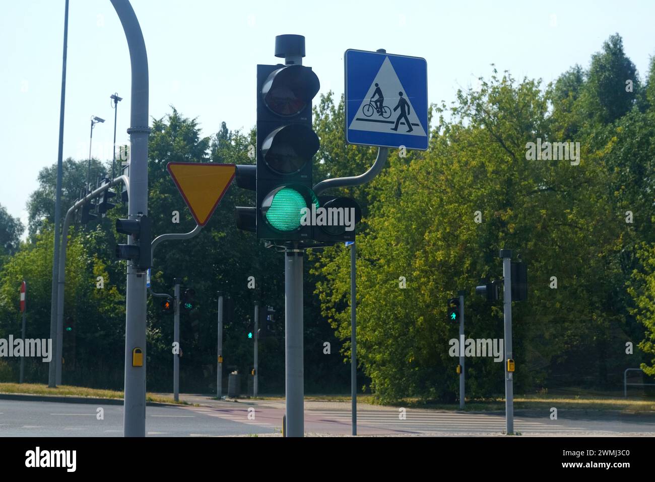 A red, yellow, and green traffic light standing on the side of a road ...