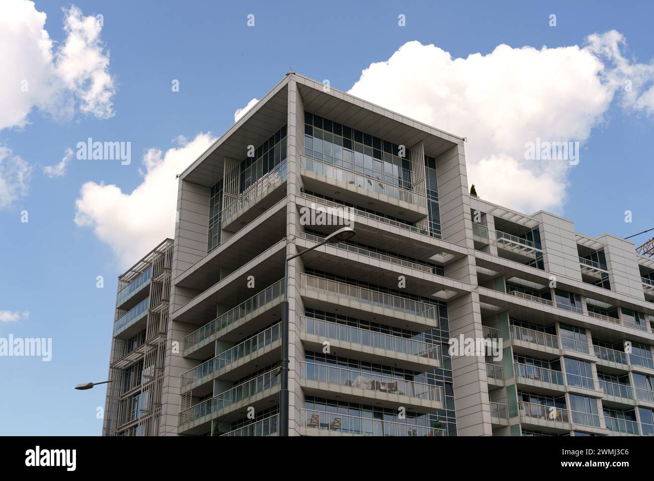A tall building featuring balconies on multiple levels with additional balconies on the rooftop ...