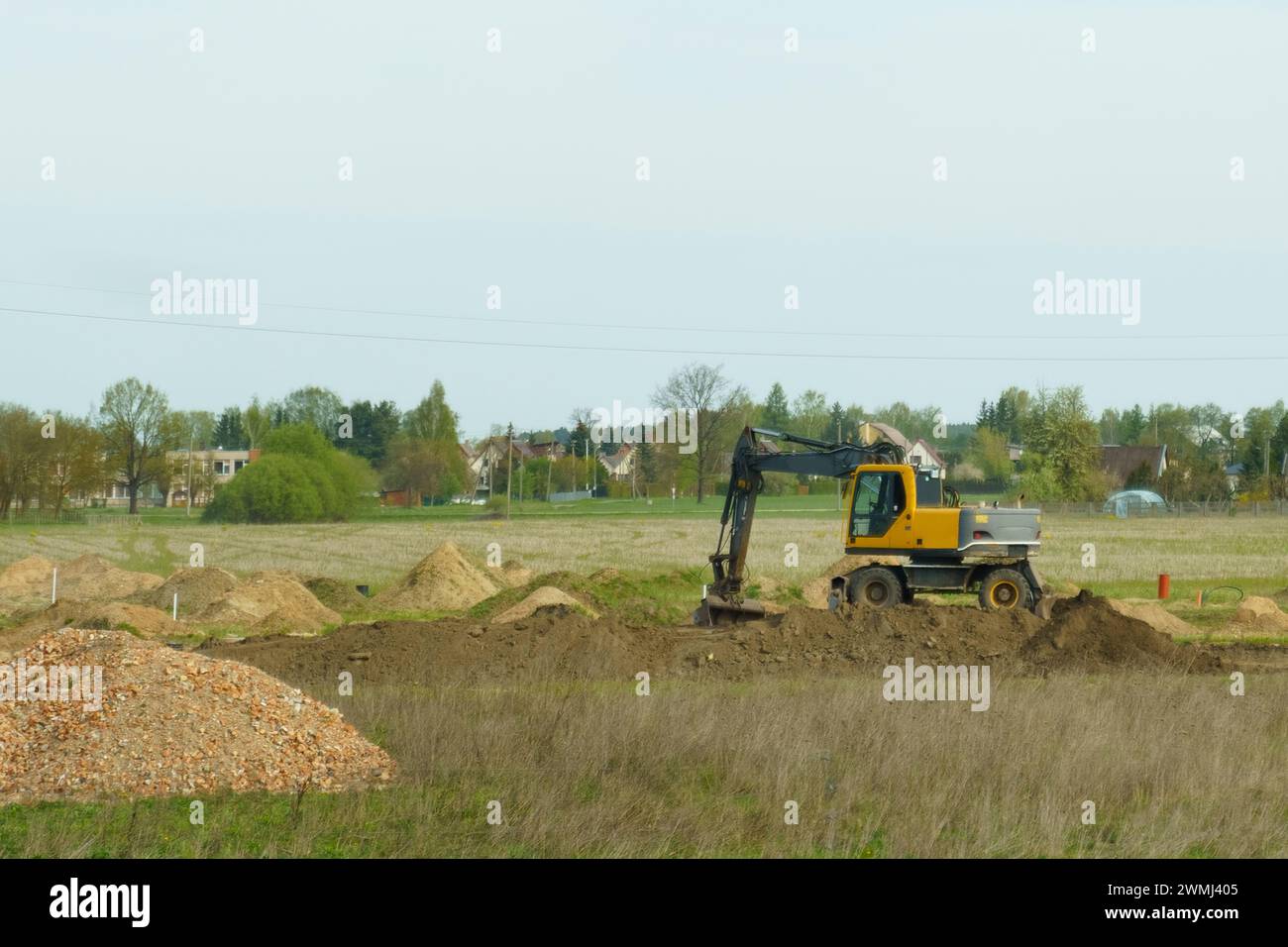 An excavator is at work on a construction site with mounds of earth ...