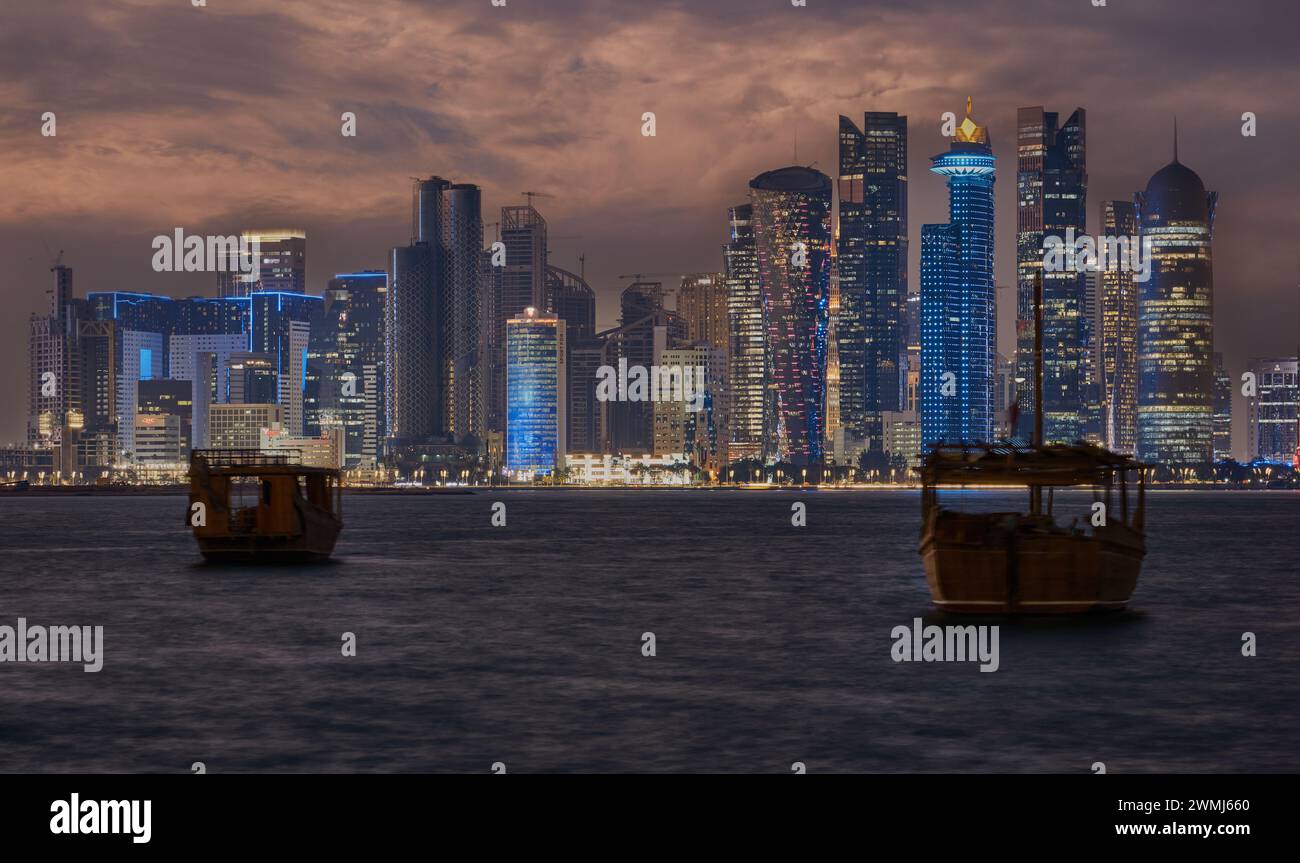 Doha, Qatar skyline from the corniche promenade at night with dhows and ...