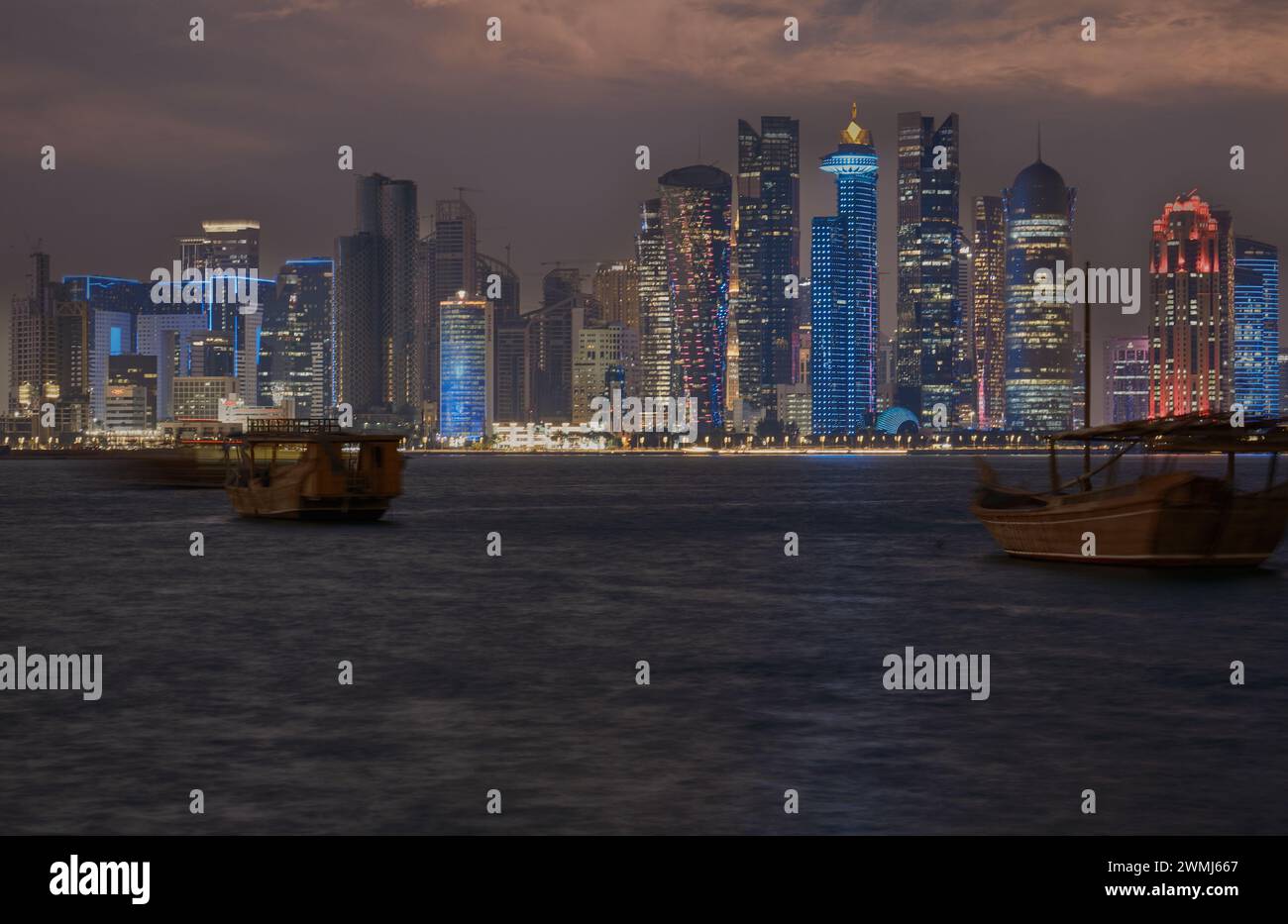 Doha, Qatar skyline from the corniche promenade at night with dhows and ...