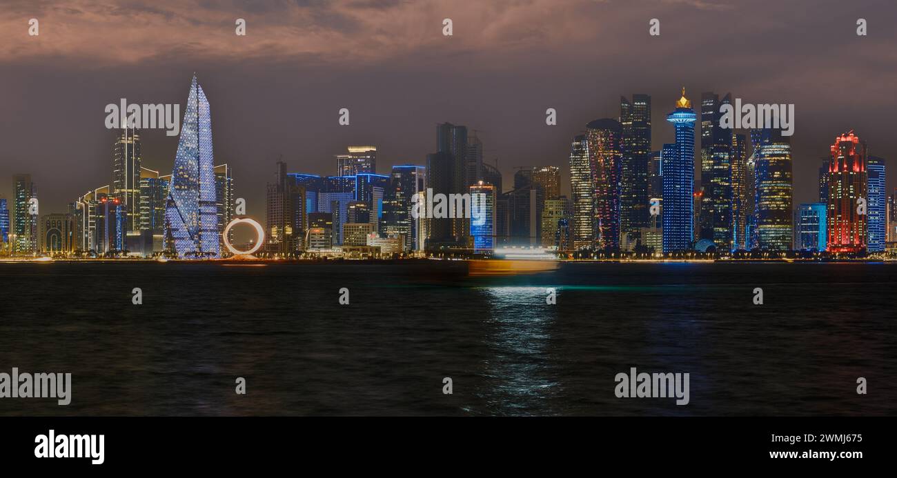 Doha, Qatar skyline from the corniche promenade at night with dhows and ...