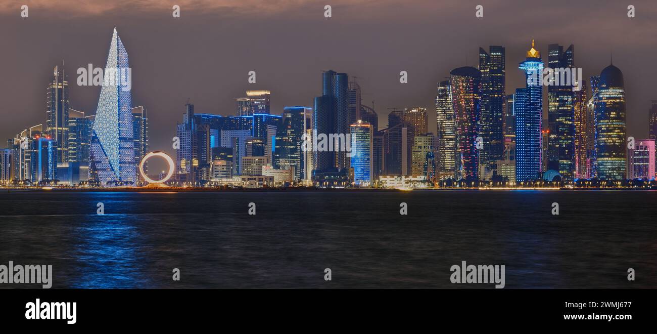 Doha, Qatar skyline from the corniche promenade at night with dhows and ...
