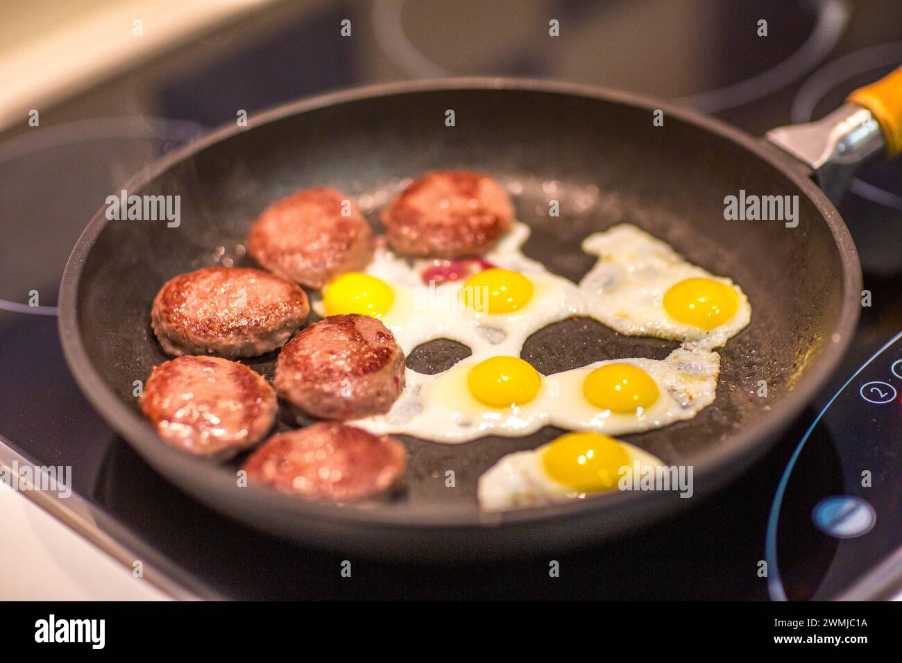 Sizzling mini burgers and quail eggs cook on a stovetop Stock Photo - Alamy