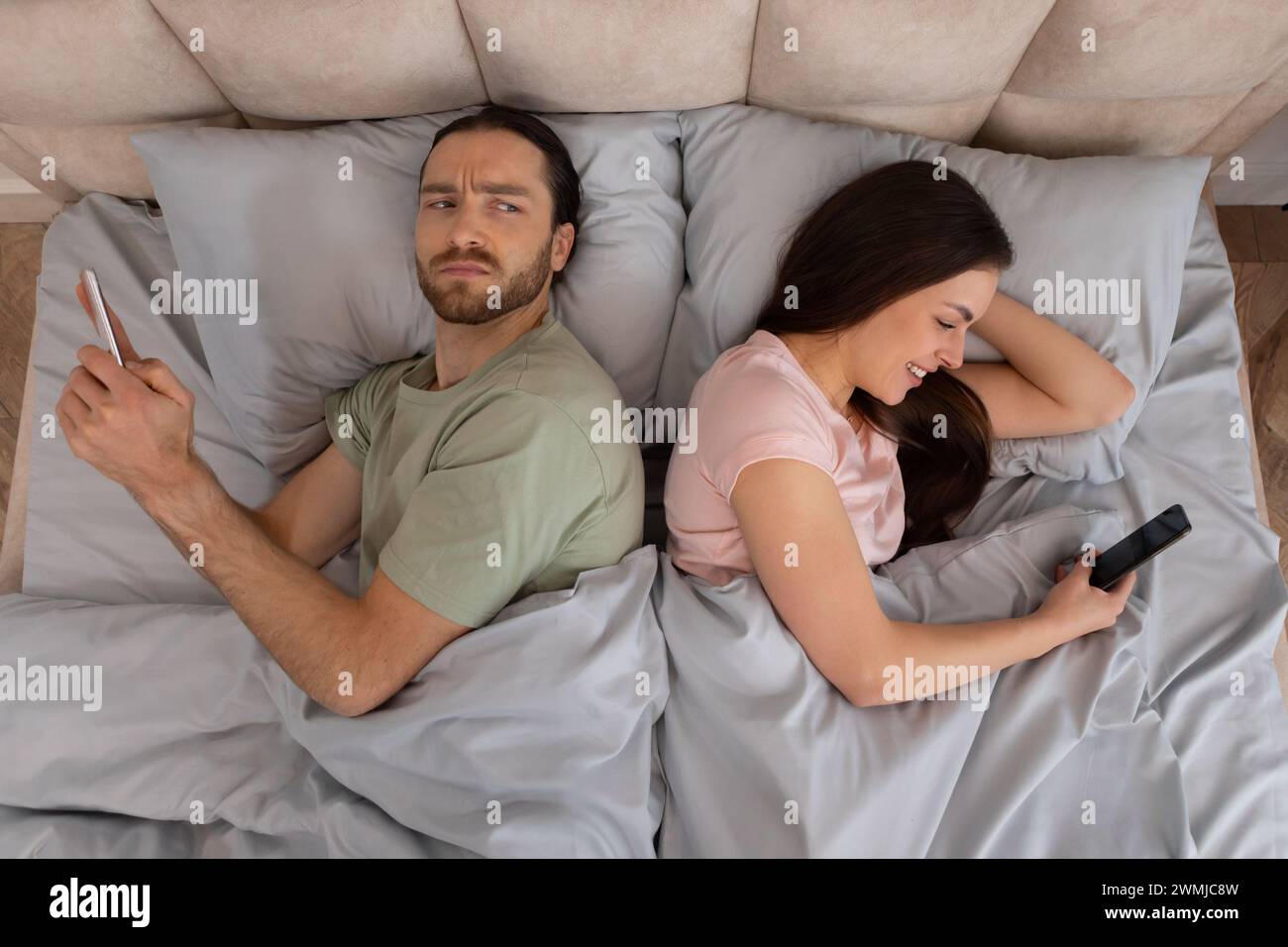 Discontent young couple using phones in bed, disconnected Stock Photo ...