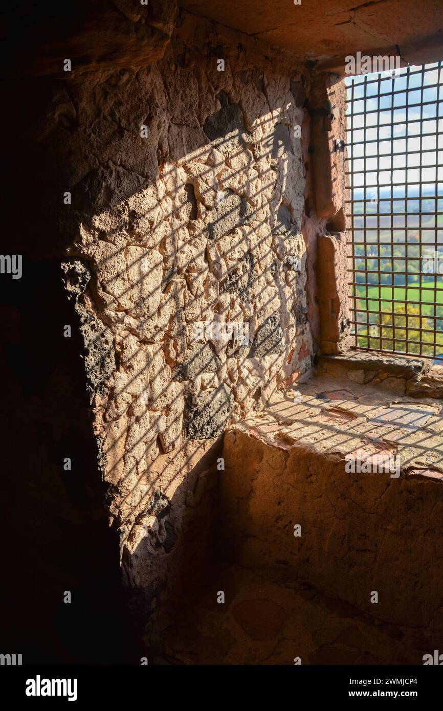 Sun shines through an old castle window with bars with shadows on the ...