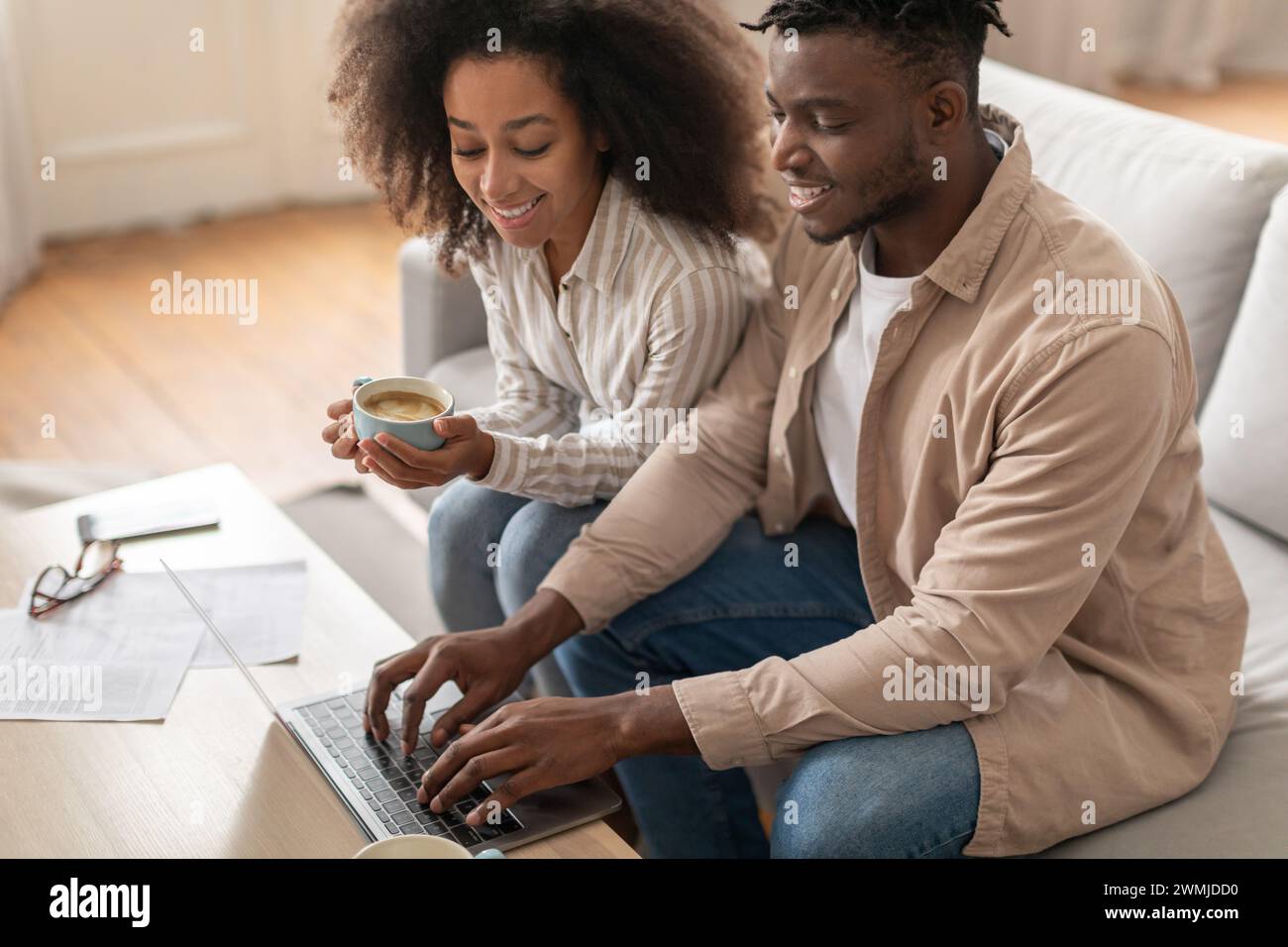 Black couple engaged with paperwork and laptop in living room Stock ...