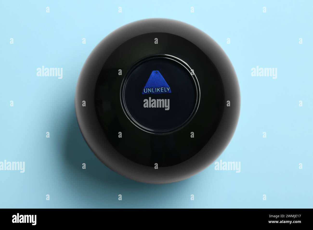 Magic eight ball with prediction Unlikely on light blue background, top ...