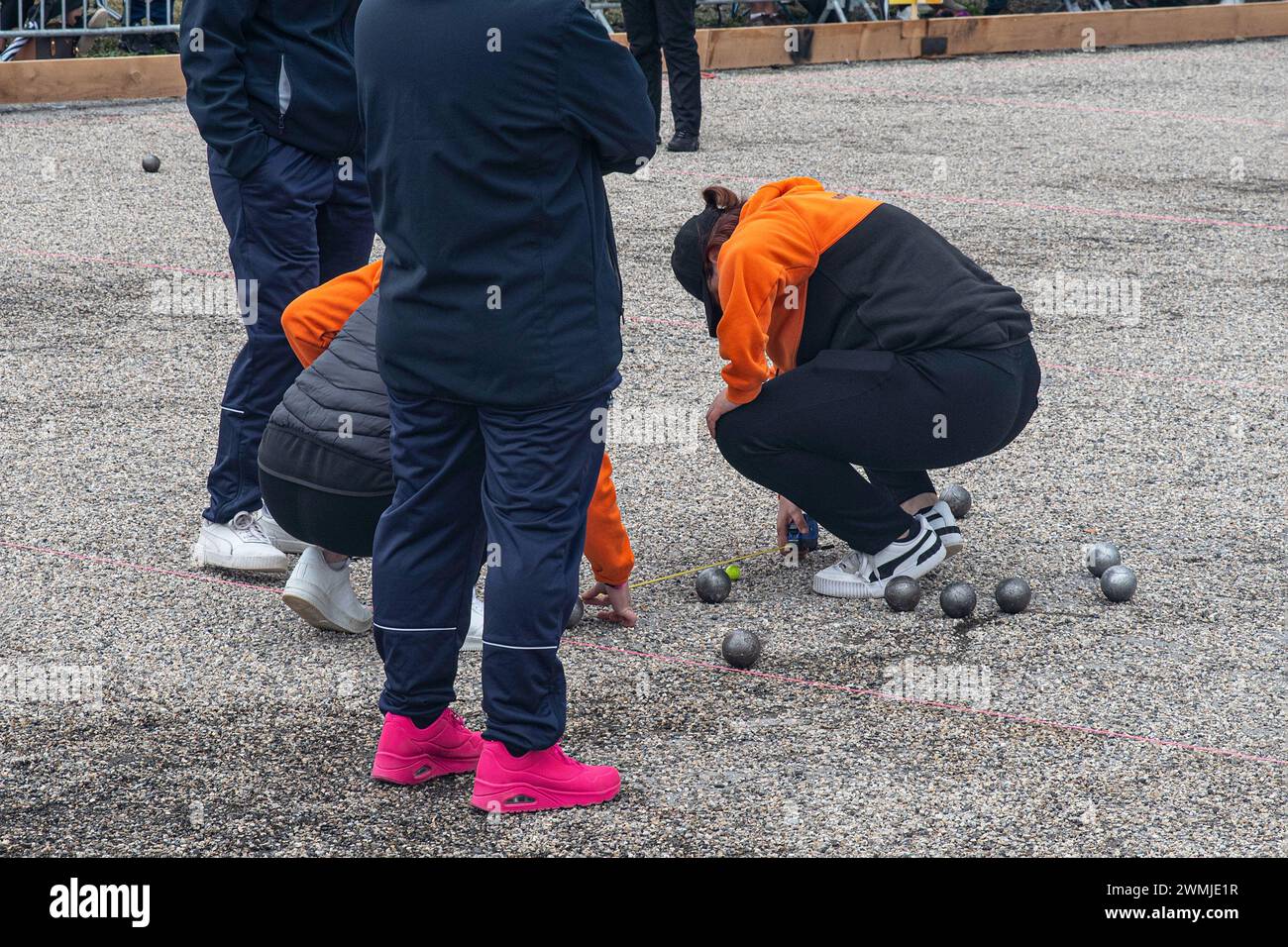 Two people use a metre to measure the distance between two boules on a ...
