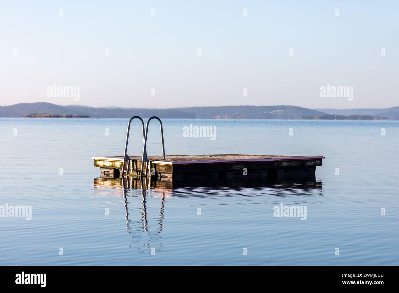 Swimming raft with ladder floating empty on the ocean Stock Photo - Alamy