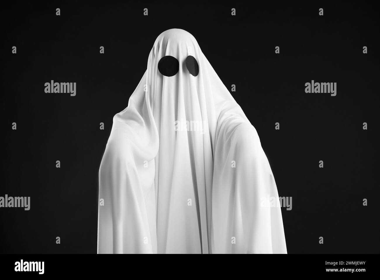 Creepy ghost. Person covered with white sheet on black background Stock ...