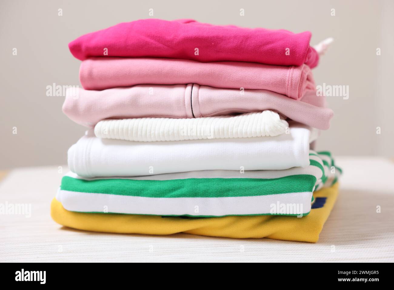 Stack of folded clothes on table against beige background Stock Photo ...